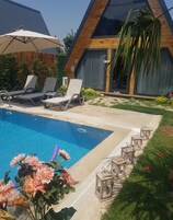 Uma piscina com espreguiçadeiras, um grande guarda-sol e lanternas decorativas.