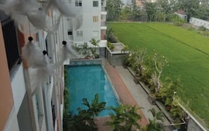 Um edifício residencial com piscina, gramado bem cuidado e vista para uma propriedade vizinha.