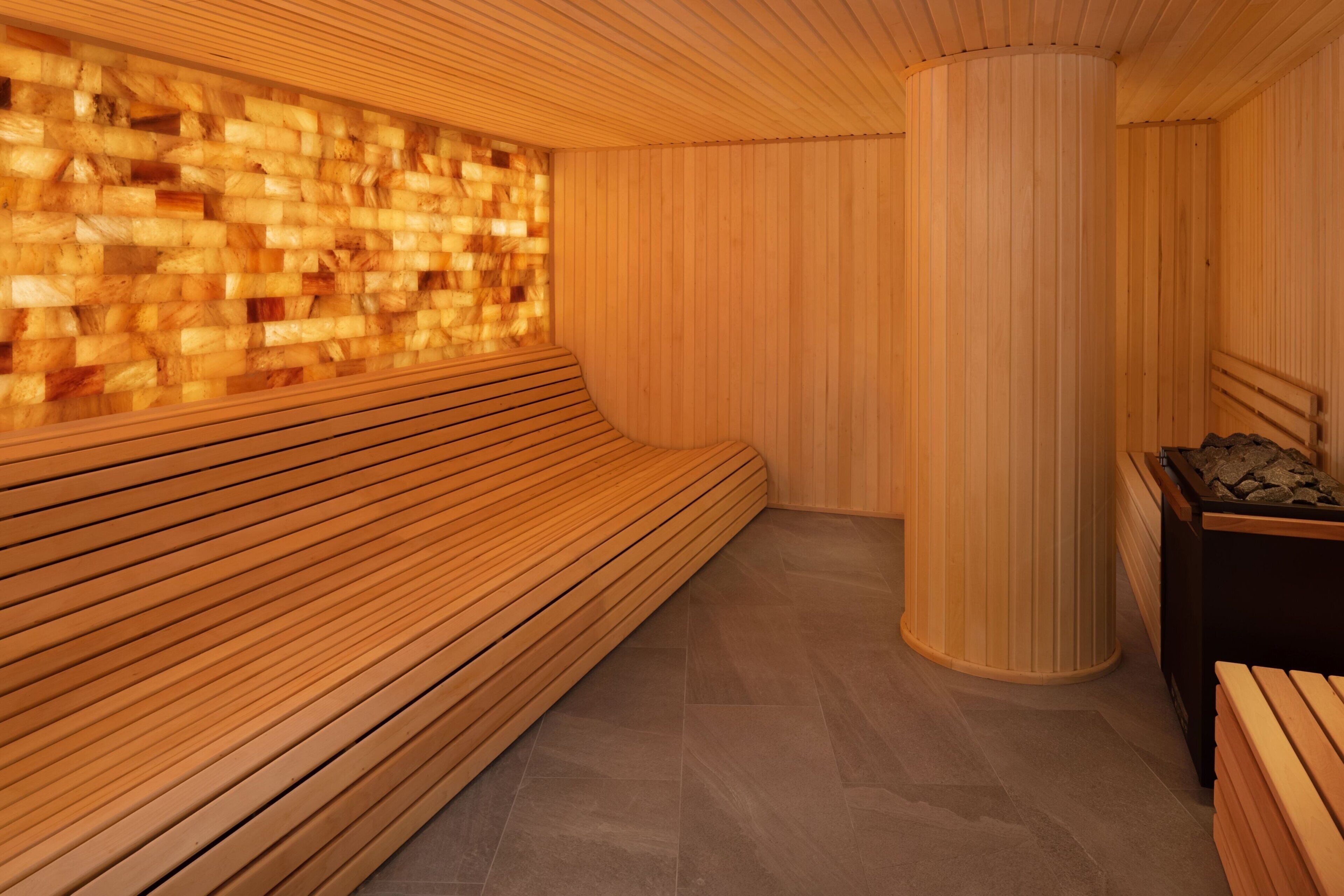 Uma sauna com bancos de madeira, piso ladrilhado e uma parede com textura.