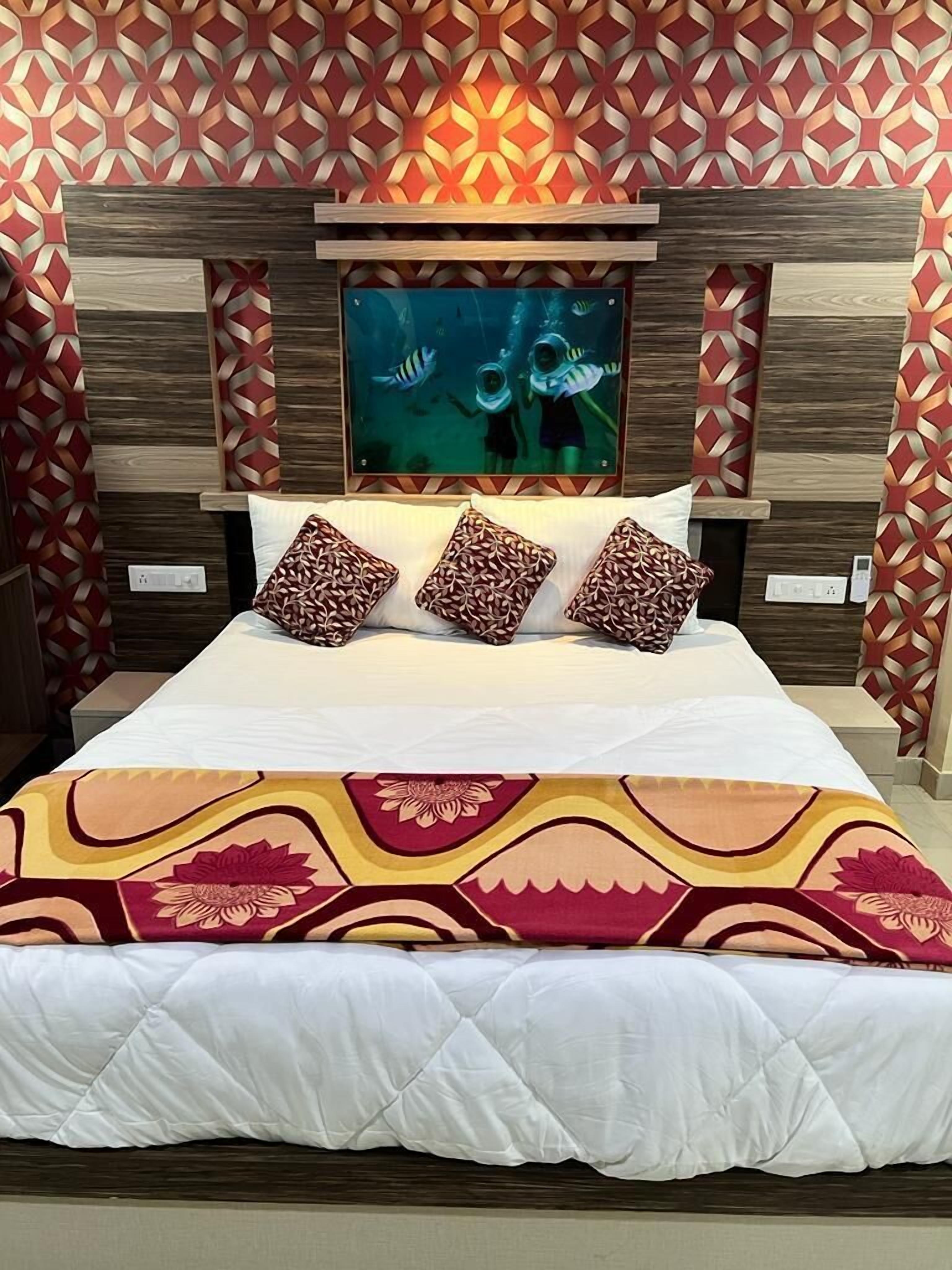 Uma cama com colcha estampada, cabeceira com um quadro emoldurado e cortinas padronizadas.
