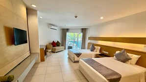 Quarto de hotel com duas camas, televisão, escrivaninha e vista para o exterior.