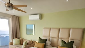Quarto com cama grande, um banco, ventilador de teto e vista para o exterior.