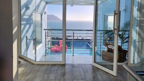 Varanda espaçosa com porta de vidro que dá para uma área de piscina, com um boi de piscina inflável vermelho e um letreiro de boas-vindas.