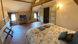 Quarto com cama, escada de madeira, parede de pedra e lareira.