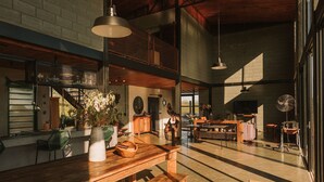 Um interior espaçoso com tetos altos, móveis de madeira e grandes janelas que permitem a entrada de luz natural.