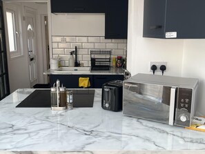 Uma cozinha moderna com bancada de mármore, uma torradeira Russell Hobbs e uma cafeteira.
