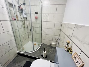 Uma casa de banho moderna com cabine de duche em vidro, sanita e lavatório.