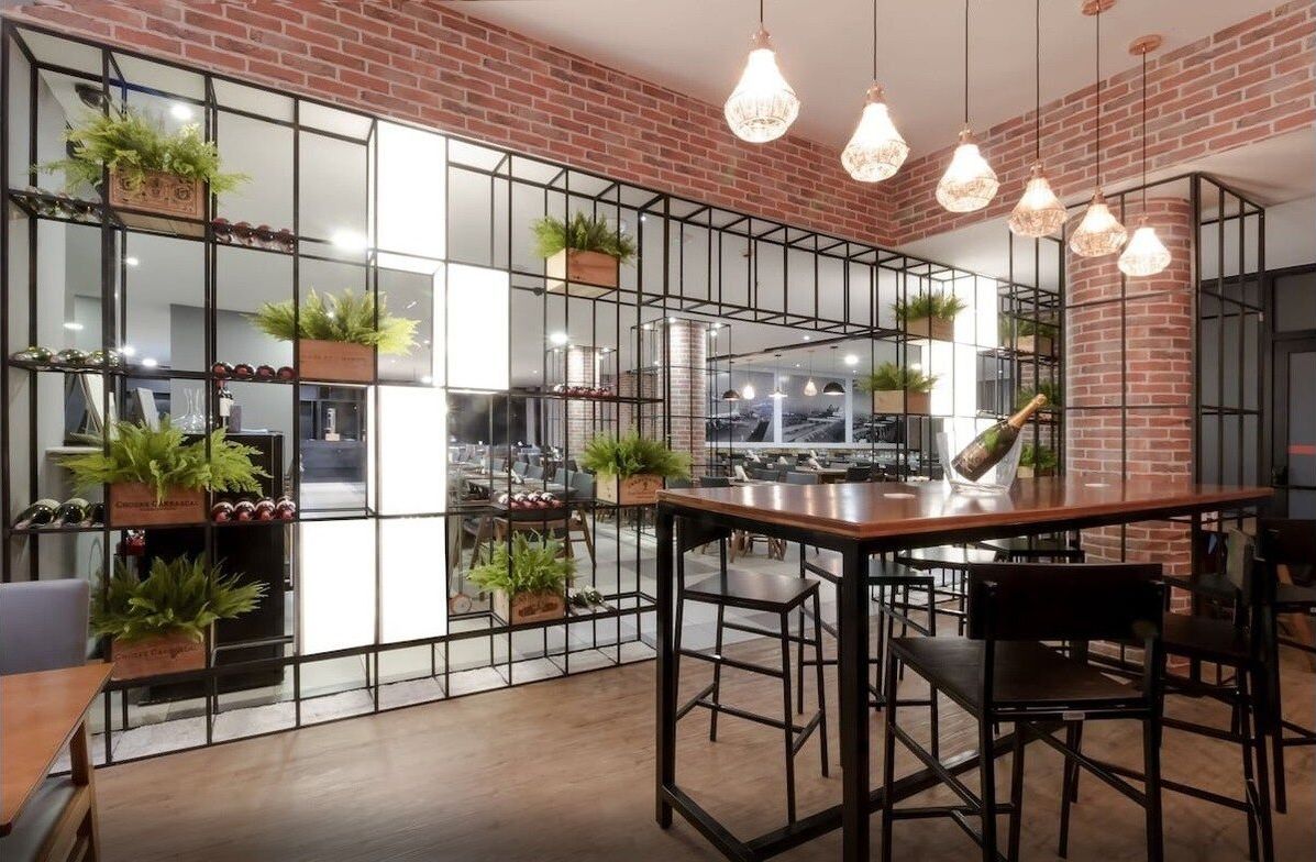Uma cozinha moderna com paredes de tijolo, janelas amplas e luminárias pendentes.