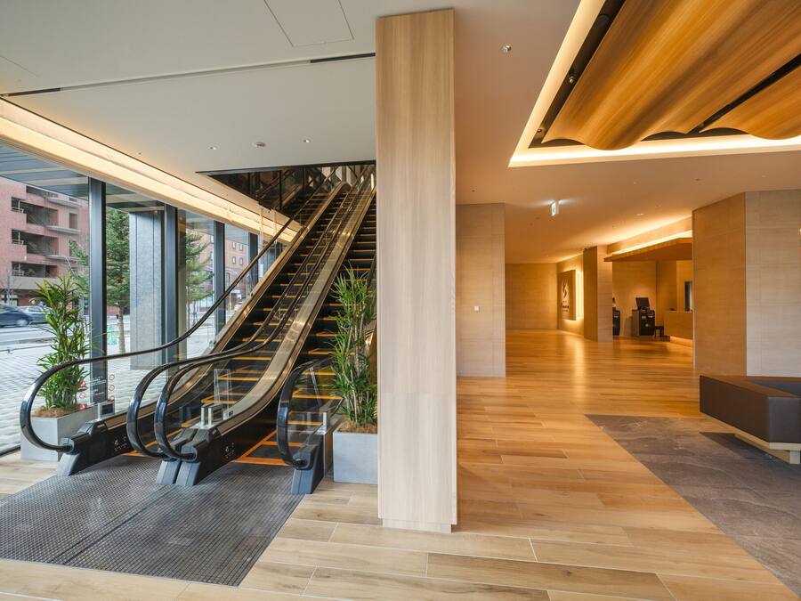 Espaço interno com escada rolante central, balcão de recepção e design de interiores moderno.