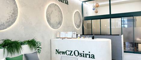 Uma área de recepção com balcão, assentos e uma parede com luminárias circulares.