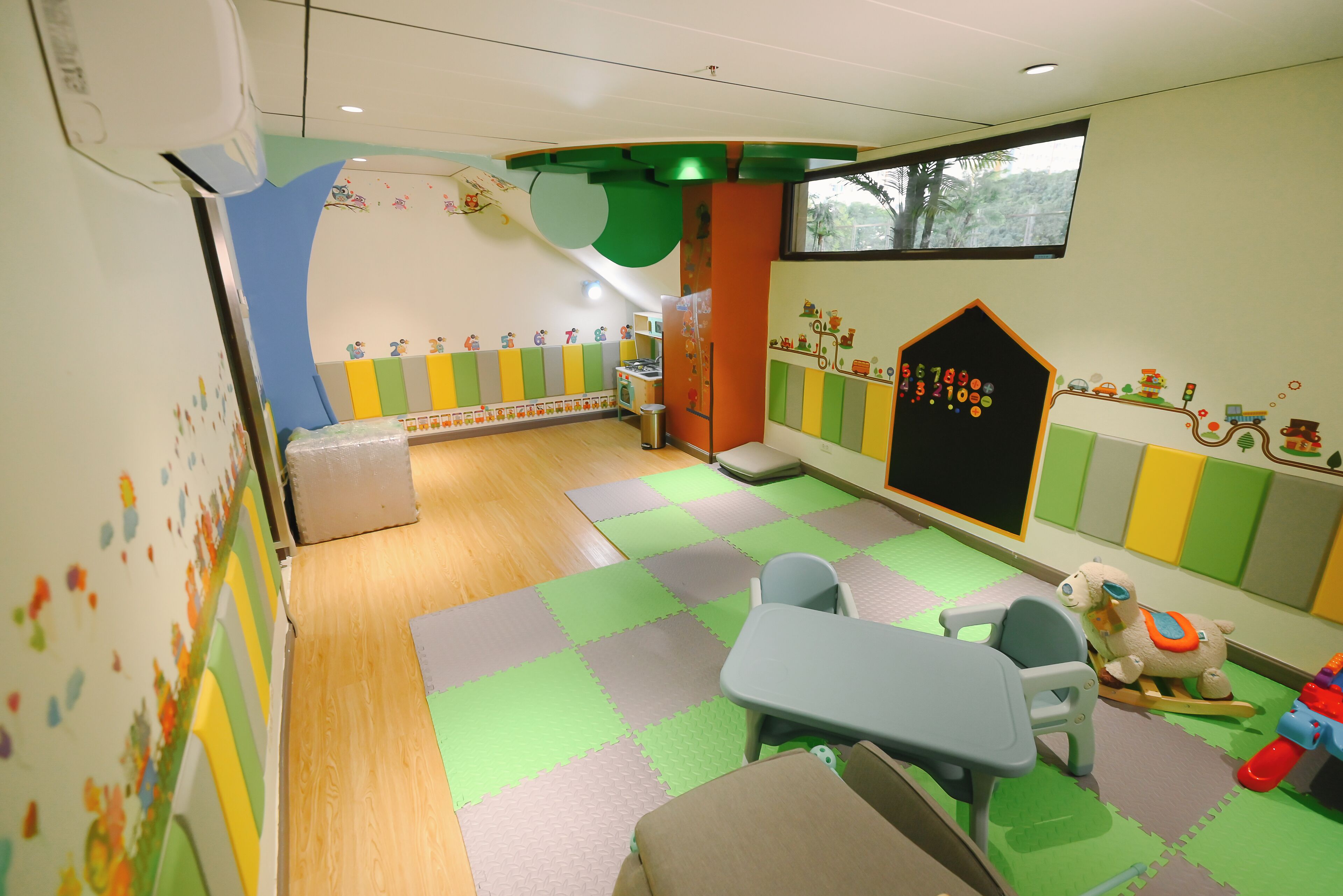 Uma sala de jogos infantil com paredes coloridas, área de recreação e janela.