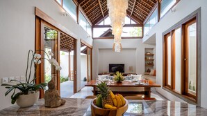 Um quarto espaçoso com área de jantar, um lustre grande e vista para o exterior.