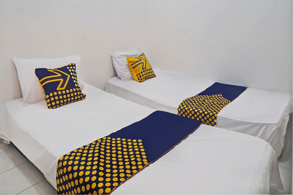 Duas camas de solteiro com roupa de cama branca e cobertores com bolinhas azuis e amarelas.