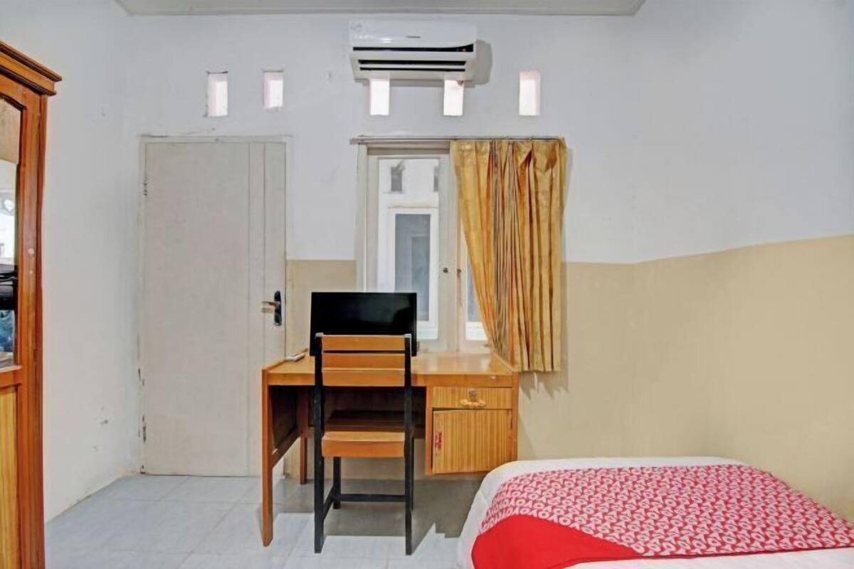 Quarto com cama, escrivaninha, cadeira, guarda-roupa e ar condicionado.