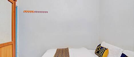 Um quarto com uma cama, almofadas e uma porta de madeira.