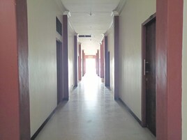Um corredor comprido e estreito com piso de azulejos e portas em ambos os lados.
