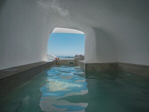 Piscina com águas cristalinas e vista do céu e da paisagem distante.