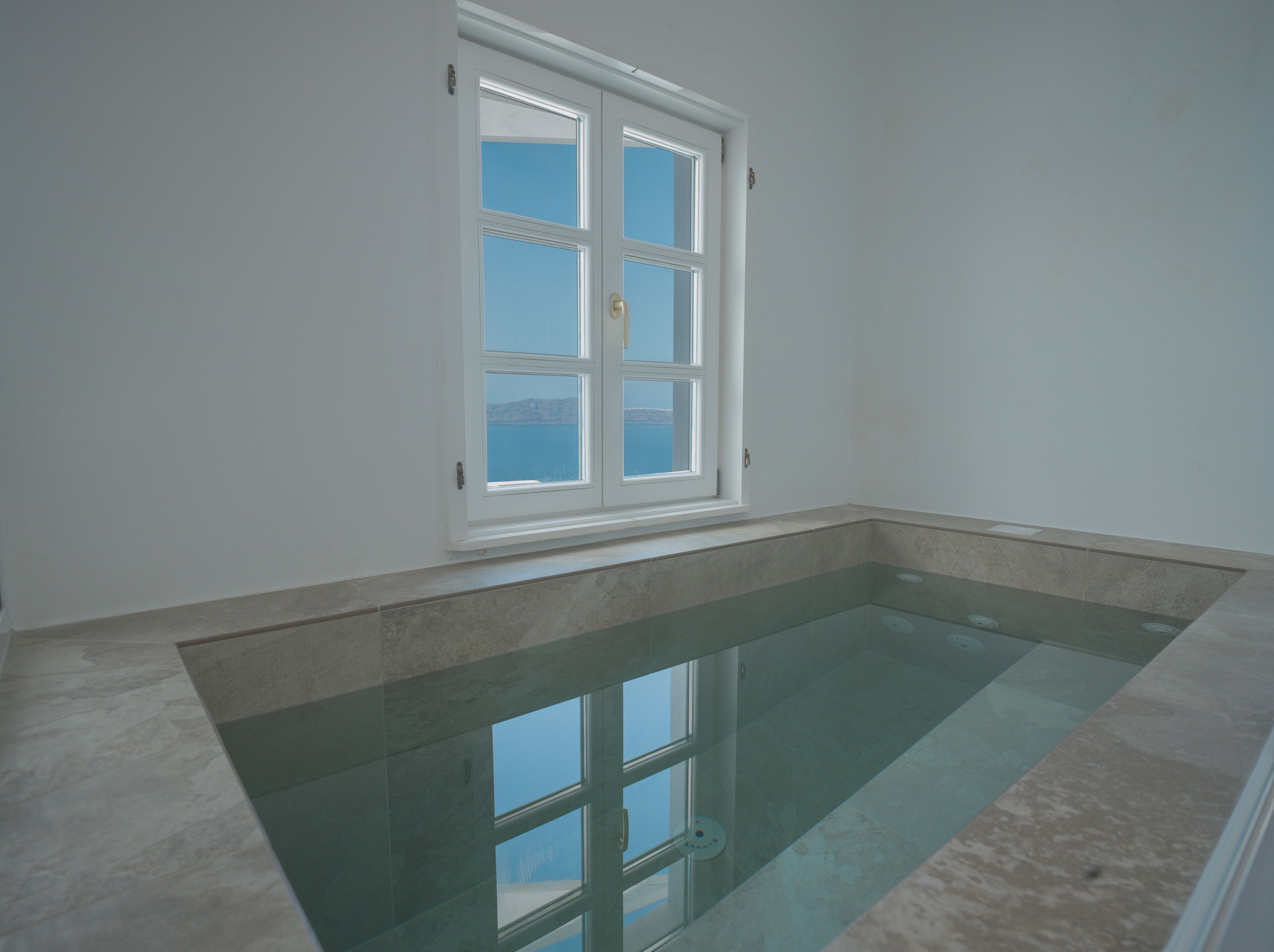 Quarto com uma janela grande e piscina com fundo de vidro.