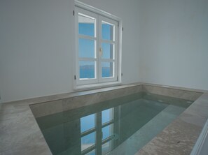 Quarto com uma janela grande e piscina com fundo de vidro.