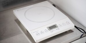 Um fogão por indução branco, com visor digital e botões de controle.