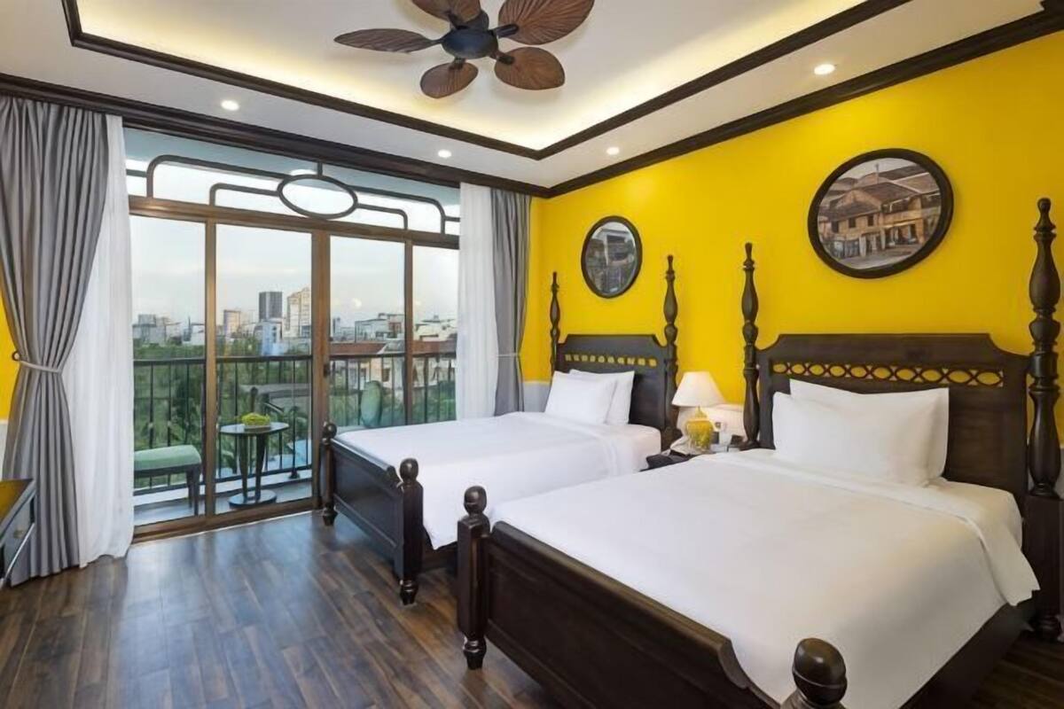 Quarto de hotel com duas camas, varanda e vista para a cidade, além de um ventilador de teto.