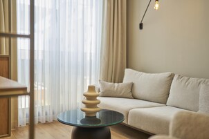 Uma sala de estar moderna com uma mesa de vidro, um sofá bege e um vaso decorativo.