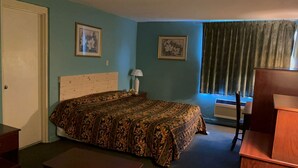 Quarto com cama, mesa de cabeceira, abajur, telefone e duas fotos emolduradas na parede.