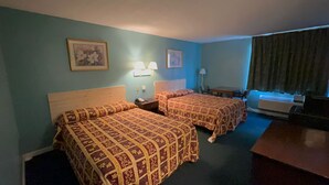 Quarto de hotel com duas camas, uma escrivaninha, uma cadeira e uma janela com cortinas.