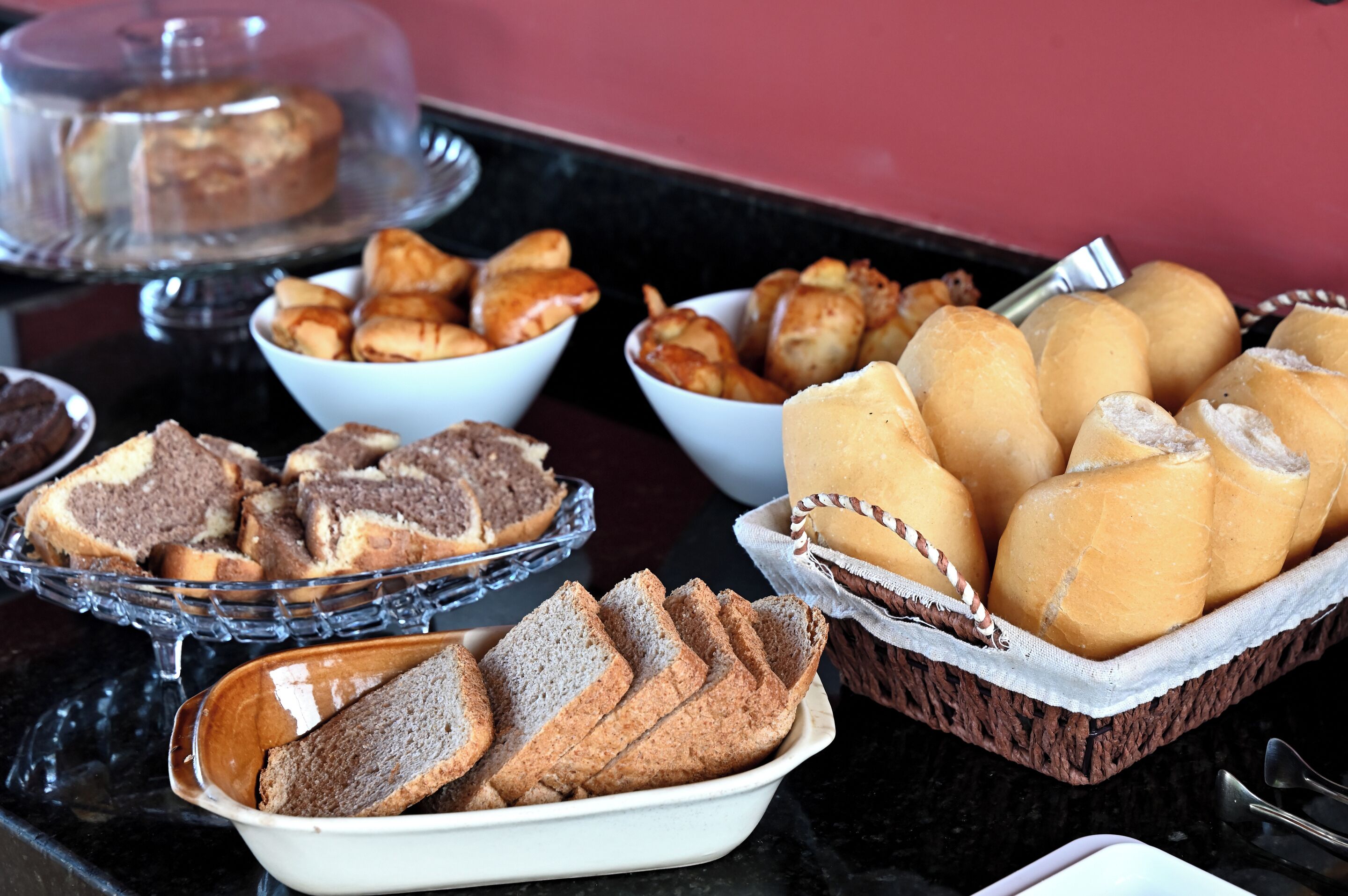 Diversos produtos de panificação, incluindo pão, doces e um bolo sobre uma mesa.
