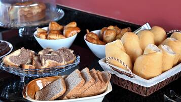 Diversos produtos de panificação, incluindo pão, doces e um bolo sobre uma mesa.