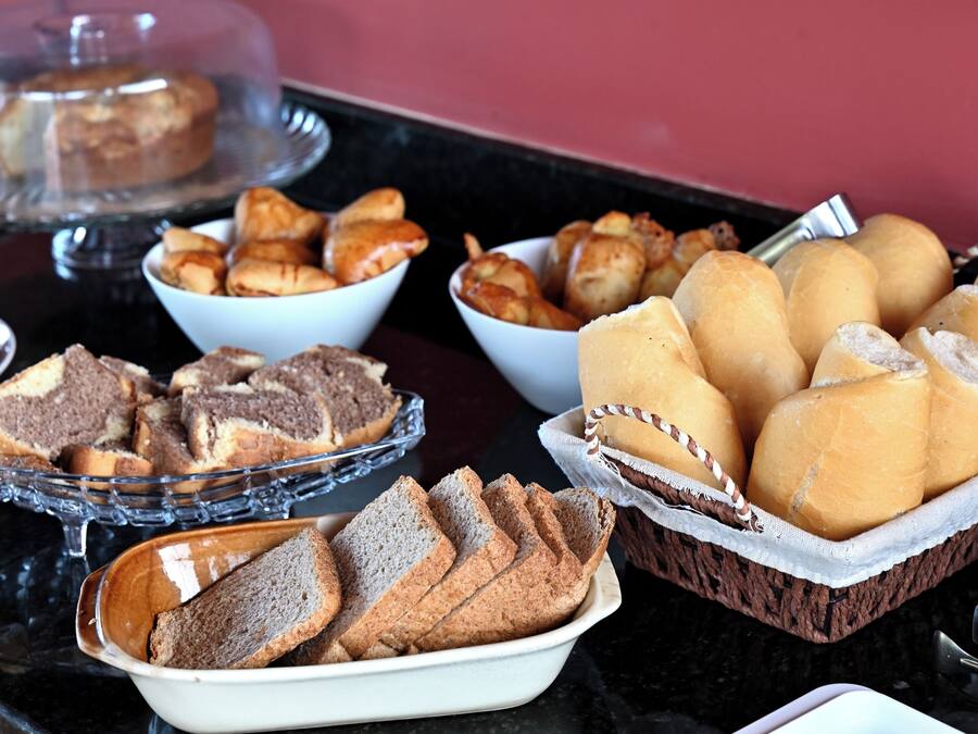 Diversos produtos de panificação, incluindo pão, doces e um bolo sobre uma mesa.
