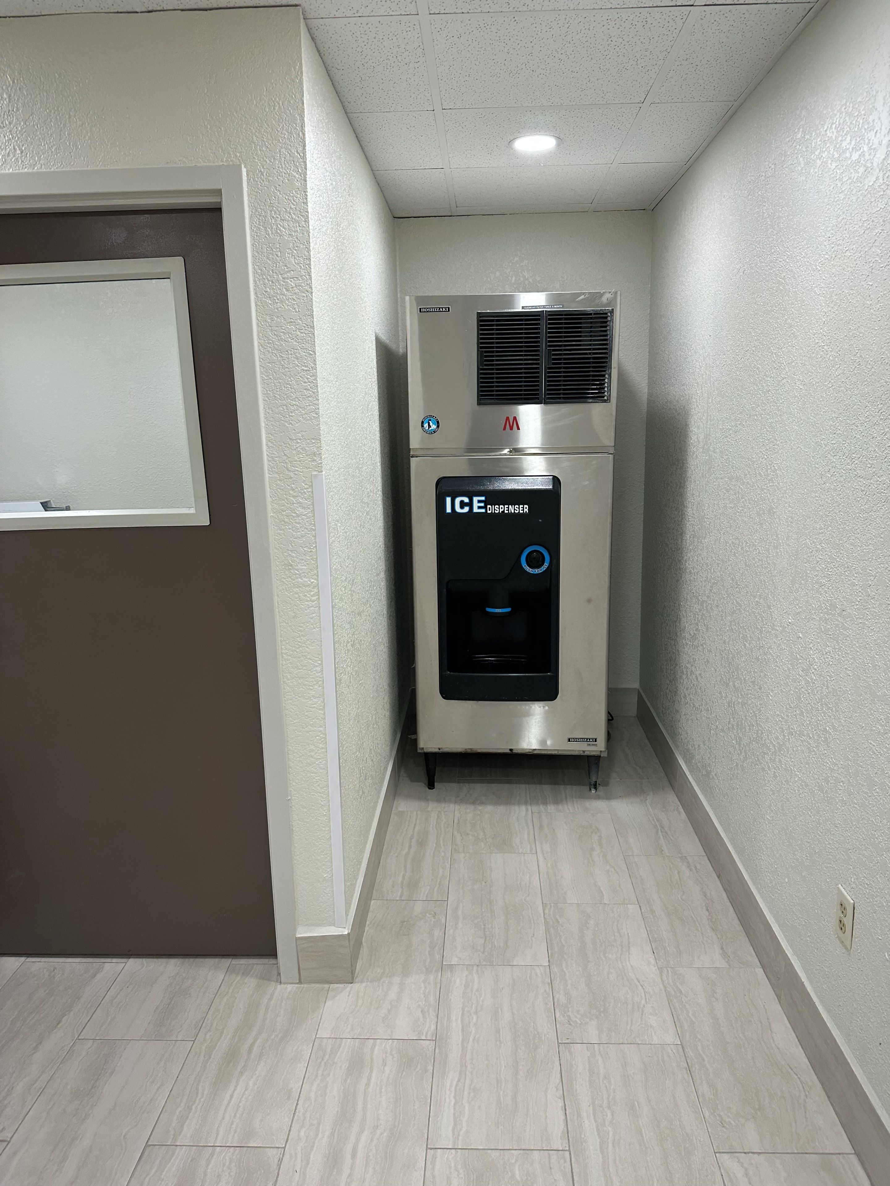 Corredor com unidade de ar condicionado na parede e dispensador de gelo.