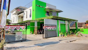 Um edifício de dois andares com fachada verde e branca, entrada com portão e aviso indicando vigilância por câmeras de segurança.