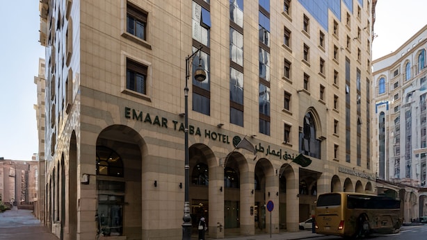 Um hotel grande com vários andares, entradas em arco e uma placa de destaque.