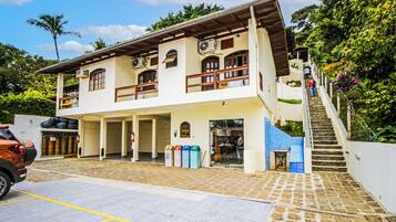 Um edifício de dois andares com entrada coberta, escadaria e área de estacionamento.