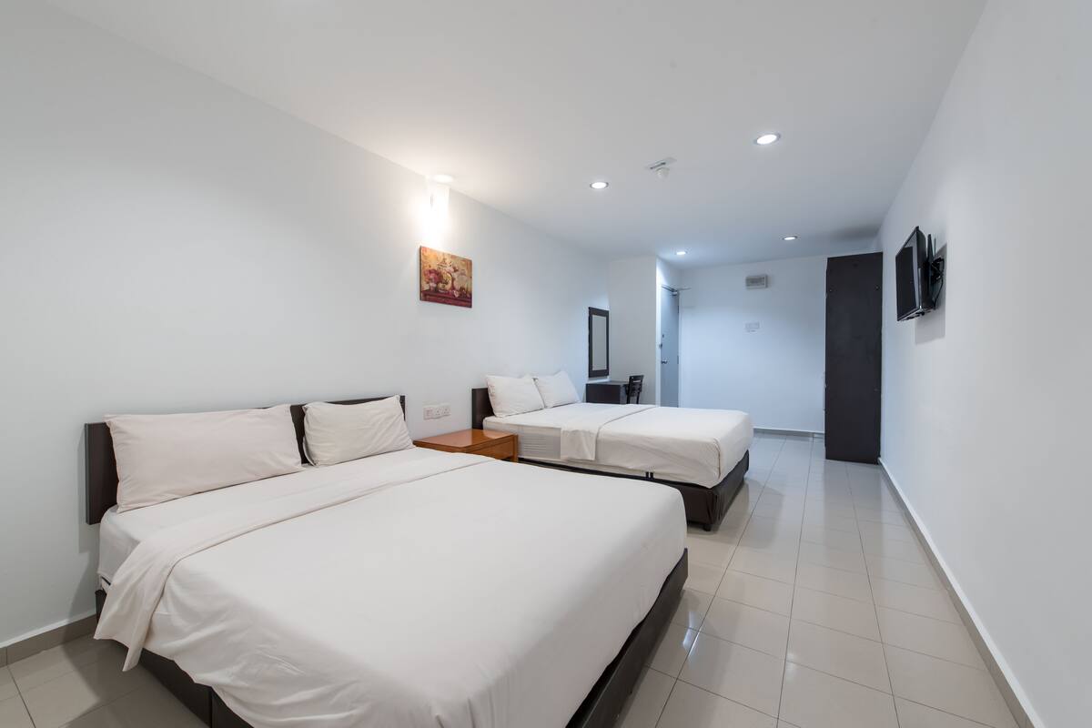 Quarto de hotel com duas camas, uma televisão fixada na parede e um quadro na parede.