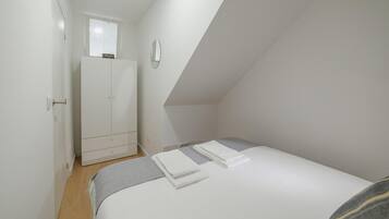 Quarto com cama, guarda-roupa, janela e espelho.