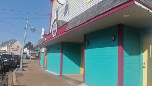 Um edifício com fachada azul-turquesa e detalhes vermelhos, com uma grande janela circular e uma placa que diz 'Captain's Cabin Restaurant'.