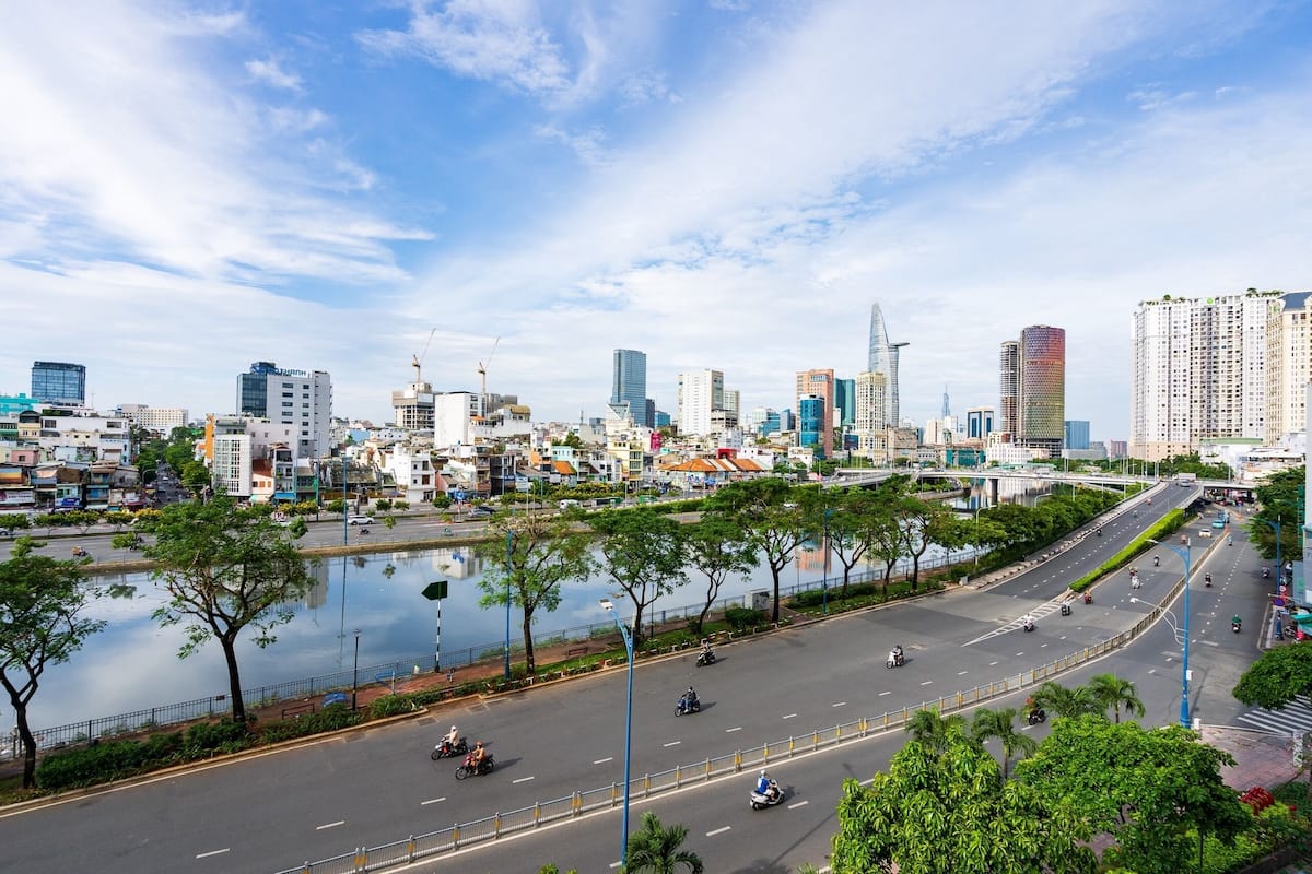 Paisagem urbana com edifícios modernos, uma avenida larga e um corpo d'água.