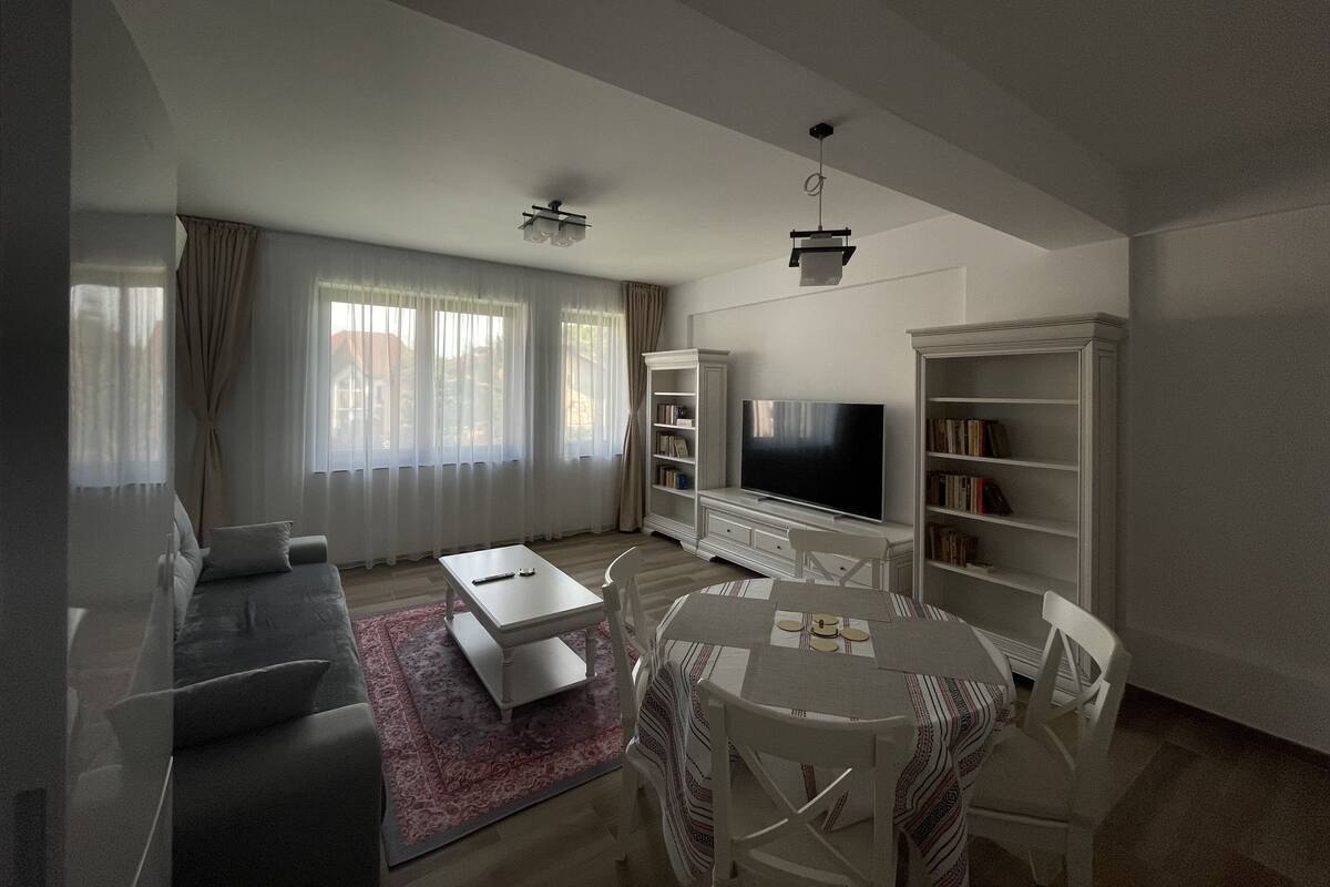 Uma sala de estar moderna com sofá, mesa de centro, televisão e estante.