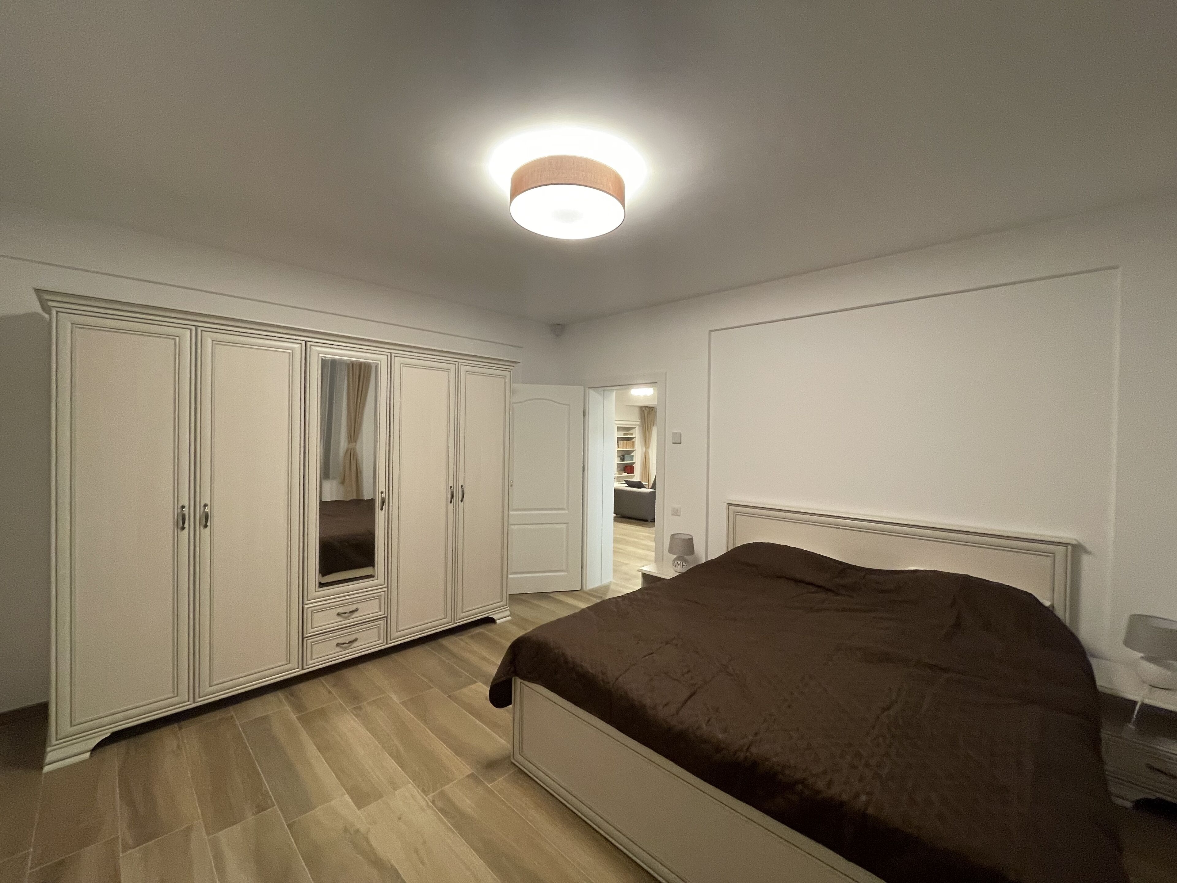 Quarto com cama, guarda-roupa e mesa de cabeceira.