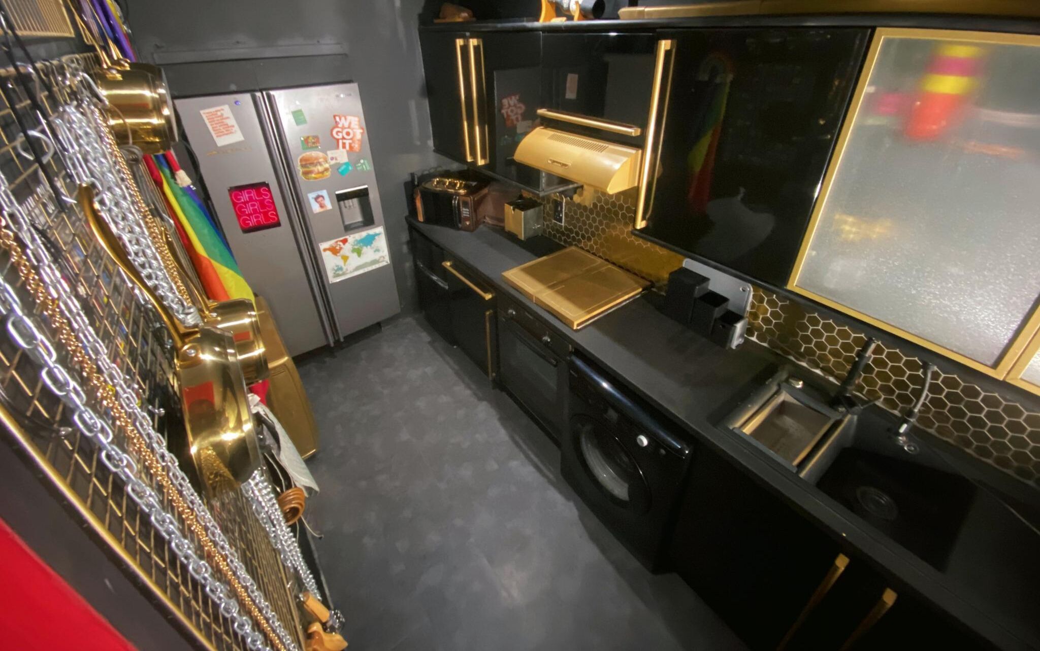 Cozinha moderna com eletrodomésticos de aço inoxidável, bancada preta e detalhes dourados.