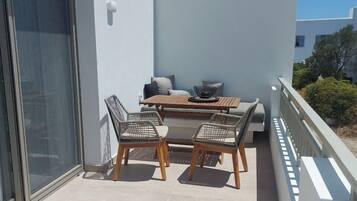Uma varanda com mesa, cadeiras, um sofá e guarda-corpo.