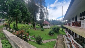 Um pátio com um gazebo, vegetação exuberante e um edifício com sacadas.