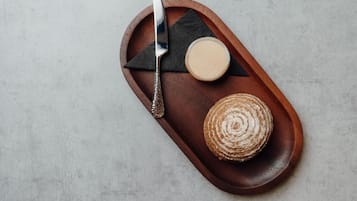 Uma bandeja de madeira com um pastel, uma faca e um pequeno recipiente de creme.