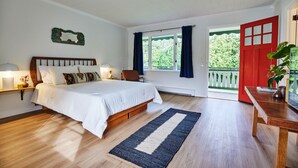 Quarto com cama, mesa de cabeceira, abajur e vista para o exterior.