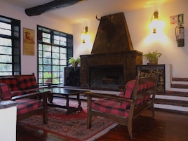 Uma sala de estar acolhedora com lareira, sofás xadrez vermelhos e pretos, uma mesa de centro de madeira e um tapete estampado.