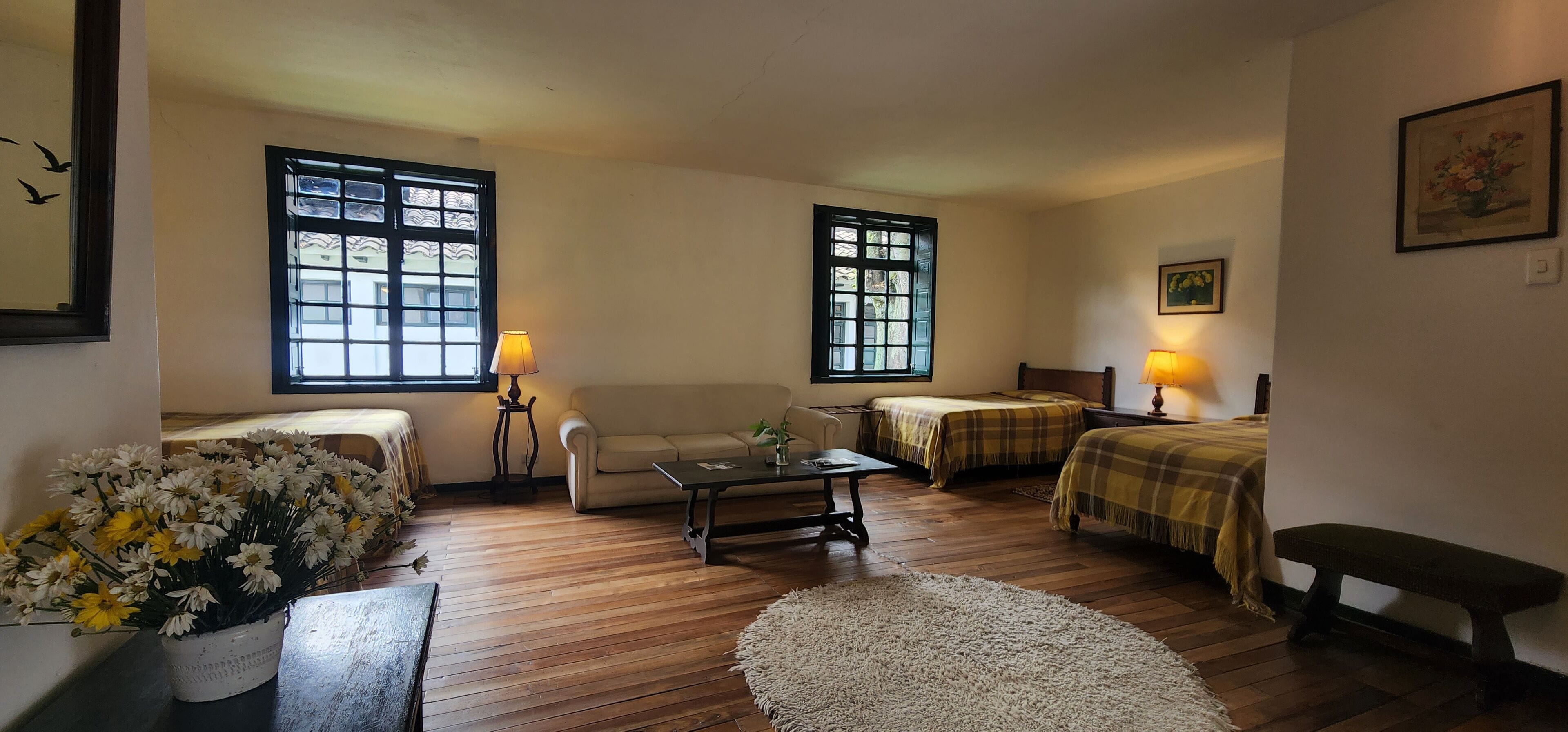 Uma sala de estar aconchegante com um sofá, duas camas, uma mesa de centro e um tapete.