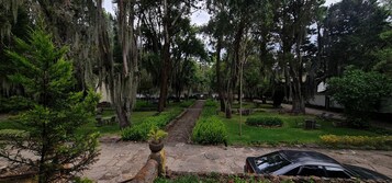 Um cemitério com calçada pavimentada, árvores e um carro estacionado.