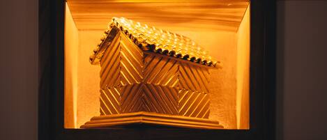 Modelo arquitetônico emoldurado de uma casa com telhado triangular e fachada em padrão de losangos.